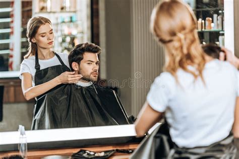 Reflection In Mirror Of Hairdresser Doing Hairstyle To Handsome Client