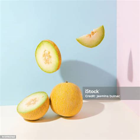 고립 된 파스텔 베이지 블루 및 핑크 배경의 공간에서 날아 다니는 멜론과 육즙이 많은 멜론 조각으로 만든 최소한의 추상적 인 창조적 인 여름 과일 개념 태양과 그림자 원시