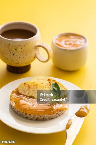 아몬드 버터와 사과를 곁들인 엉뚱한 메밀과 쌀 간식은 커피 한 잔과 함께 노란색 배경에 계피와 바질로 장식되어 있습니다 0명에