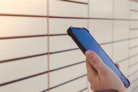 소포 사물함 옆에있는 휴대 전화를 들고있는 여성 손 쇼핑 사물함에서 소포를 수집합니다 바코드 리더와 휴대 전화 셀프 서비스 로커 셀에 여성 스칸 Qr 코드 현대 배송 및