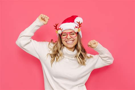 흰색 따뜻한 스웨터와 빨간 산타 모자를 쓴 한 젊은 여성이 손을 들고 기뻐합니다 크리스마스와 새해 컨셉 크리스마스에 대한 스톡 사진 및 기타 이미지 Istock