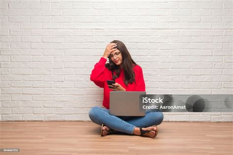 노트북과 스마트폰 손으로 머리에 강조를 사용 하 여 바닥에 앉아 젊은 갈색 머리 여자는 수치심과 깜짝 얼굴로 충격 분노와 좌절 두려워 하 고 실수에 대 한 화가 노트북에