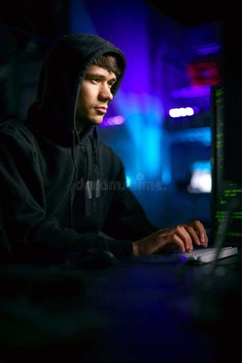 Low Key Lighting Shot Of Male Computer Hacker Sitting In Front Of Screens Breaching Cyber