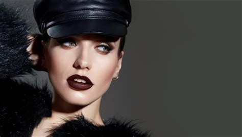 یک دختر جوان سکسی زیبا با موهای مجلل روان روی پس زمینه مشکی دراز کشیده که توسط سیب های طلایی