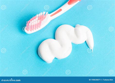 A Small Smear Of Toothpaste And Toothbrush On A Blue Background Stock