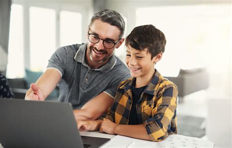 가상 수업 학습 및 거실에서의 지식을위한 인터넷이있는 아버지와 자녀와의 교육 학습 및 노트북 기술 교육 및 아이디어를 위해 가정에서 아빠와 학생과 온라인 부모에 대한 스톡