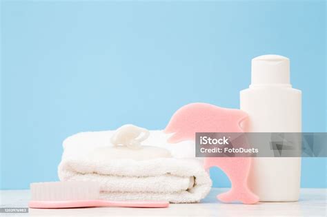 베이비 세탁 액세서리 분홍색 돌고래 스폰지 샴푸 병 헤어 브러시 흰색 수건 및 밝은 파란색 벽에 선반에 젖꼭지 파스텔 색상입니다 근접 촬영 전면 뷰입니다 텍스트의 빈