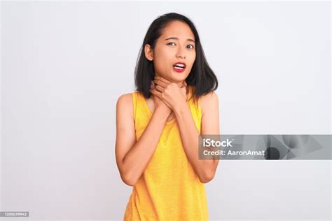 노란 캐주얼 티셔츠를 입은 젊은 중국 여성이 고립된 흰색 배경 위에 서서 고통스러운 목졸림 때문에 외치고 질식합니다 건강 문제 질식 과 자살 개념 T 셔츠에 대한 스톡 사진