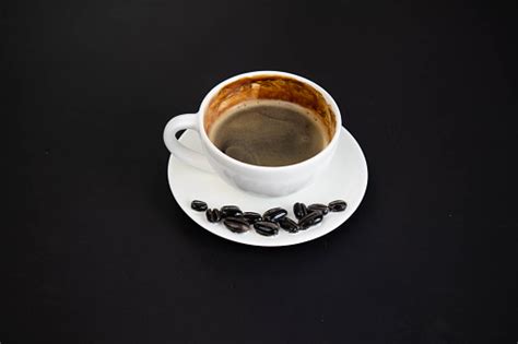 검은 색 배경에 향기로운 갓 갈은 아라비카 커피의 화이트 컵 컵은 접시에 있습니다 검은 색 배경에 향기로운 갓 갈은 아라비카 커피의 화이트 컵 맨 위 보기입니다 0명에 대한