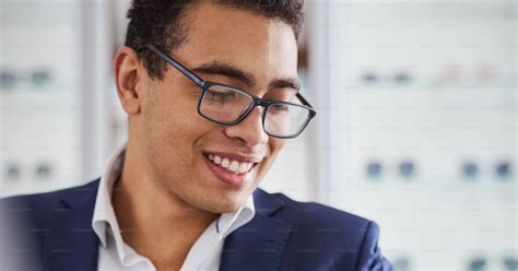 검안 사무실에 앉아 손에 핸드폰을 들고 웃고 있는 잘생긴 남성 고객 사진 Unsplash의 잘 생긴 남자 이미지