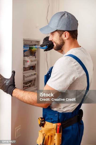 배전반에서 퓨즈를 점검하는 동안 초점을 맞춘 유니폼을 입은 전기 기술자 전기 연료 및 전력 생산에 대한 스톡 사진 및 기타 이미지 전기 연료 및 전력 생산 분전반