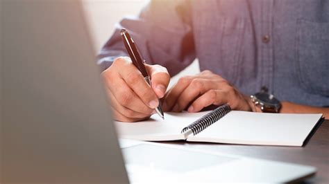 노트북 종이 나 편지에 필기 펜 메모를 사용하여 사람의 손을 클로즈업 테이블 데스크 사무실에 일기 학생 복사 공간이있는 작가를위한 직장 비즈니스 작업 및 학습 교육 개념