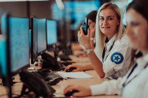 Group Of Security Data Center Operators Working In A Cctv Monitoring Room Looking On Multiple