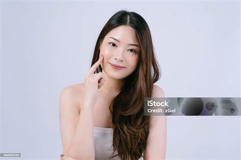 흰색 바탕에 깨끗하고 신선한 피부를 가진 행복한 아름다움 장발 아시아 여성 예쁜 한국 여자는 손가락으로 뺨을 가리키고 카메라를 보고 있다 페이셜 트리트먼트 미용 뷰티 및