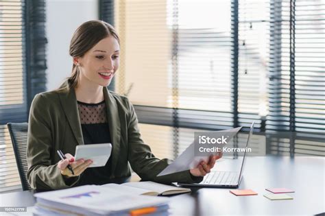 세련된 드레스를 입은 성공한 사업가가 노트북 컴퓨터를 사용하여 현대적인 사무실의 책상에 앉아 있다 그녀는 작업 프로젝트를 계획하는 성공적인 재무 관리자 인 것 같습니다 25