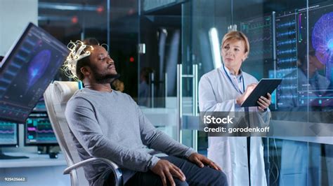 남자 착용 브레인 웨이브 스캔 헤드셋 앉아 과학자 태블릿 컴퓨터 감독 과정 동안의 자에 에 현대 뇌 연구 실험실 모니터 표시