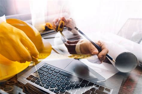 사무실 책상에 있는 건설 현장의 건축 프로젝트에서 데이터 작업 및 태블릿 노트북에 대해 논의하는 두 명의 동료 프리미엄 사진