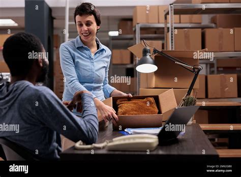 Storehouse Worker Putting Clothes In Cardboard Box Preparing Packages For Delivery While