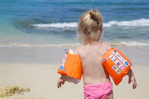 해변에서 하루를 즐기는 행복한 유아의 솔직한 초상화 팽창식 완장을 입고 바다로 달리는 소녀 백 뷰 부낭에 대한 스톡 사진 및 기타 이미지 Istock
