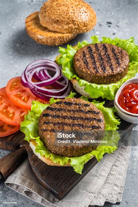 나무 서빙 보드에 비건 구운 패티 토마토 양파를 곁들인 고기 없는 버거를 재배합니다 회색 배경 위쪽 보기 비거니즘에 대한 스톡 사진 및 기타 이미지 Istock