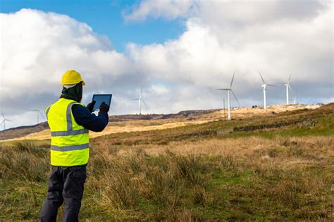 풍력 발전 단지 근처의 원격 위치에서 작업하는 동안 디지털 태블릿을 사용하는 남자의 뒷모습 엔지니어에 대한 스톡 사진 및 기타 이미지 엔지니어 지속 가능한 자원