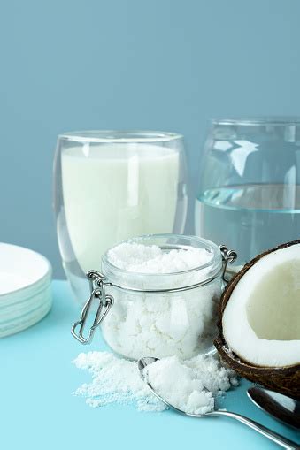 코코넛 제품 고기가 반으로 자른 오픈 코코넛 유리 항아리에 코코넛 파우더 푸른 배경에 우유를 심는 다 등등 투영 공간을 복사합니다 개념 대체 우유 식물성 가루로 빻은에 대한