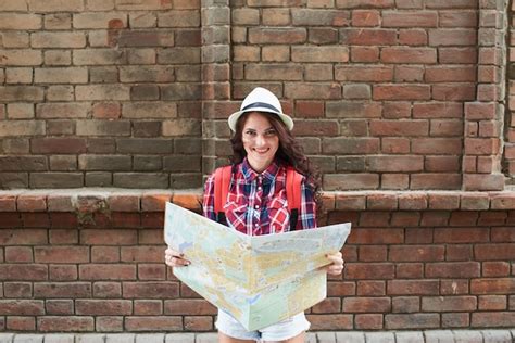 Retrato De Uma Garota Turista Com Um Chap U Segurando Um Mapa E Olhando Para Ela No Fundo De