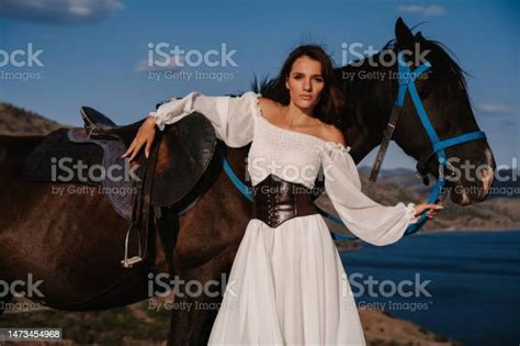 낭만적 인 소녀는 산과 바다 풍경을 배경으로 말 옆에 포즈를 취합니다 승마의 개념 예술적 사진 책과 잡지를위한 기성품 표지 여자에 대한 스톡 사진 및 기타 이미지 Istock