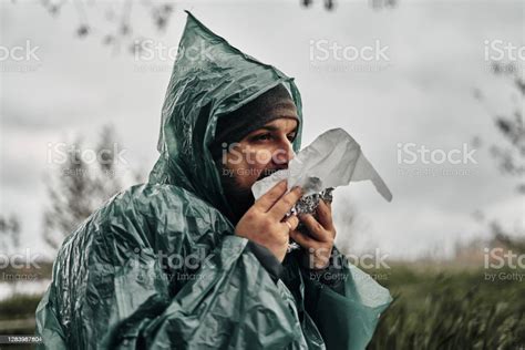 녹색 비옷을 입은 수염을 가진 남자가 자연에서 먹는다 흐린 날씨 패스트 푸드 30 34세에 대한 스톡 사진 및 기타 이미지