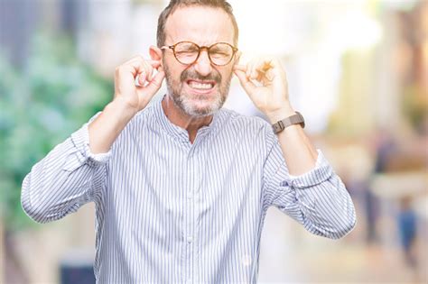 중 년 노인의 수석 사람 시끄러운 음악의 소음에 대 한 짜증이 식이 손가락으로 귀를 덮고 격리 된 배경 위에 안경을 쓰고 청각