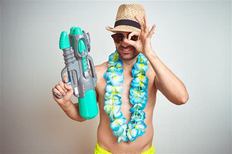 여름 모자를 쓰고 하와이 안 레이 꽃은 손가락을 통해 보고 눈으로 확인 기호를하고 행복한 얼굴 미소와 고립 된 배경 위에 물 총을 들고 개념에 대한 스톡 사진 및 기타