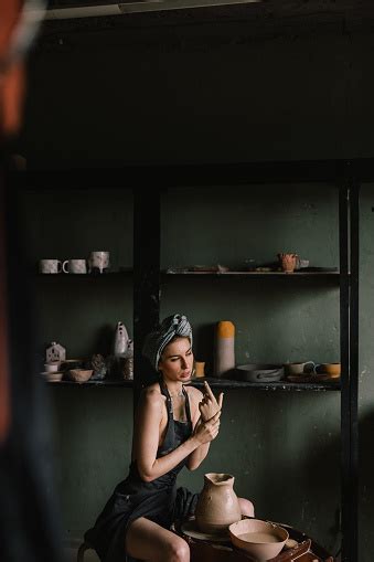 젊은 조각가 그녀의 머리와 검은 앞치마에 붕대를 가진 소녀 큰 창 근처 도자기 워크샵에서 점토 제품을 조각 컨셉 취미 조각 30