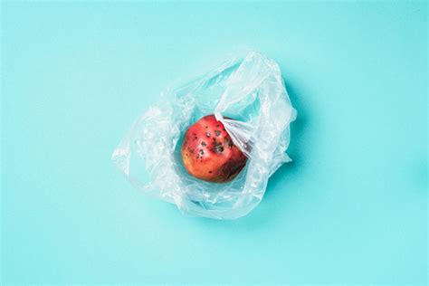 파란색 배경에 비닐 봉지에 나쁜 빨간 사과를 버릇 쓰레기 덤프 썩은 음식 맨 위 보기 공간을 복사합니다 썩은 야채와 과일 개념 폐기물 제로 퇴비 가방에 대한 스톡 사진 및