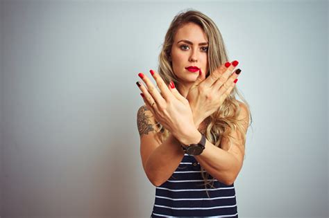 흰색 고립 된 배경 거부 표정 을 건너 팔과 손바닥을 통해 서 줄무늬 티셔츠를 입고 젊은 아름다운 여자는 부정적인 기호 화가 얼굴을하고 T 셔츠에 대한 스톡 사진 및 기타