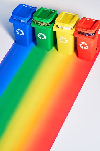 4개의 컬러 코딩 된 재활용 쓰레기통 복사 공간이있는 기하학적 무지개 종이 배경에 대한 등색 투영 빨간색 파란색 노란색 및 녹색 쓰레기통에 재활용 기호 0명에 대한 스톡