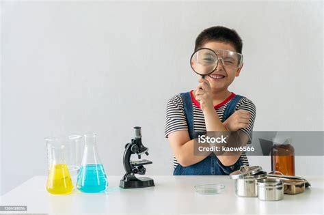 교육 과학자 개념 과학 실험실에서 뭔가를 보면서 책상에 현미경과 튜브 실험으로 그의 손 앞면 보기 눈에 돋보기를 들고 어린 아이 과학 소년 6 7 살에 대한 스톡 사진 및