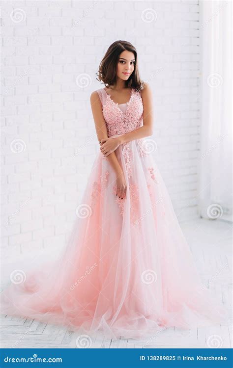 Роскошная девушка брюнета с качается стрижка представляя в дорогом розовом платье с открытой