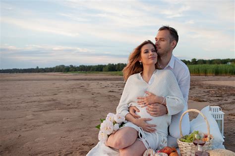 피크닉 사랑 부드러움 부부는 격자 무늬에 앉아있다 남자는 그녀의 배에 그의 손으로 임신 한 여자를 포옹 2명에 대한 스톡 사진