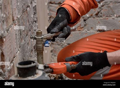Plumber Repairing Leaking Water Connection On Site Wearing Gloves And