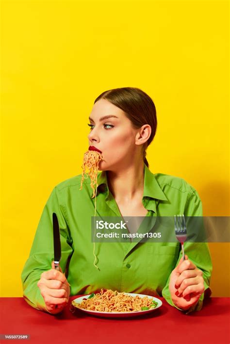 스파게티를 먹는 어린 소녀 노란색 배경 위에 입에서 튀어나온 국수 저녁 시간 이탈리아 음식 애호가 음식 팝 아트 사진 스파게티에