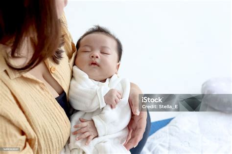 어머니는 갓 태어난 아기를 팔에 안고 침실의 침대에서 그와 함께 놀고 사랑스러운 가족 엄마와 아이가 함께 시간을 보내고 부모는 아이를 돌보고 출산 후 뚱뚱한 몸매를 가진