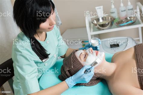 미용사는 스파 살롱에서 아름 다운 젊은 여자에 얼굴에 마스크를 적용합니다 화장품 절차 스킨 케어입니다 미세 박피 술 건강관리와