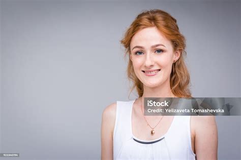 근접 촬영 세로 젊고 아름 다운 비즈니스 여자 Lred 곱슬 머리 스튜디오에서 회색 배경에 얼굴에 주 근 깨와 학생 오픈 어깨에