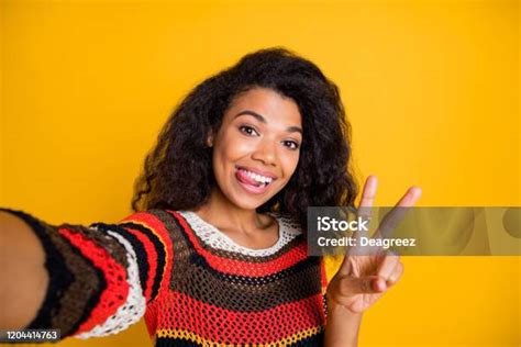 닫기 사진 의 재미 펑키 미친 여자 블로거 인플루언서 휴식 여가 시간을 가지고 셀카 찡그린 얼굴 을 만드는 V징후 비디오 통화 착용 스트라이프 스웨터 고립 된 노란색 색상