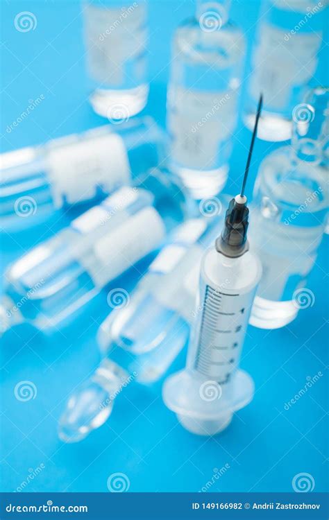 Glass Medicine Vials And Syringe On Blue Background Vertical Stock