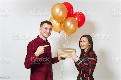 아름 다운 젊은 행복 미소 커플 사랑에 여자와 남자와 황금 선물 상자를 들고 제시 하 고 빨강 노랑 흰색 바탕에 생일 축 하 풍선 격리 휴일 파티 개념입니다 2명에 대한