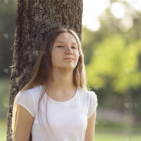 年轻的女孩靠在一棵树上