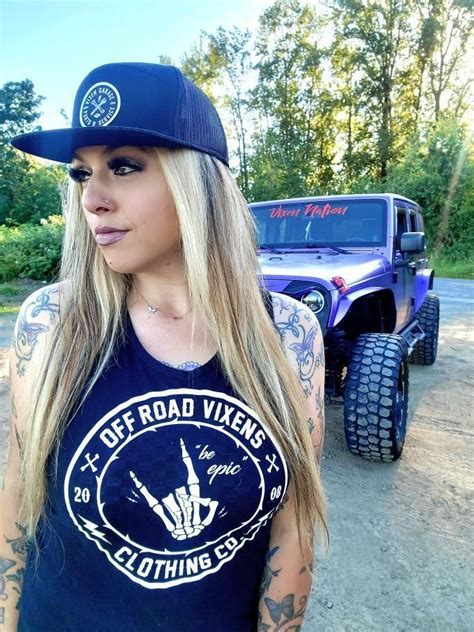 A Woman With Long Hair Wearing A Blue Shirt And Hat Standing In Front
