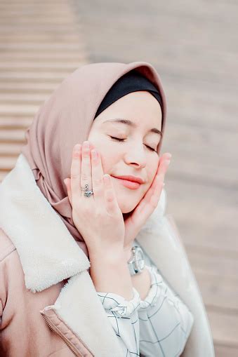 베이지 색 코트와 머리 스카프를 입은 무슬림 여성 공원에있는 세련된 무슬림 여성 벤치에 앉아있는 소녀 20 24세에 대한 스톡 사진 및 기타 이미지 Istock