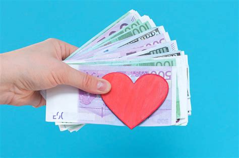 돈 큰 금액과 빨간 마음의 번들이있는 손의 클로즈업 기금 자선 재정 지원 및 지원의 기부 수평 사진 파란색 배경 가계에 대한